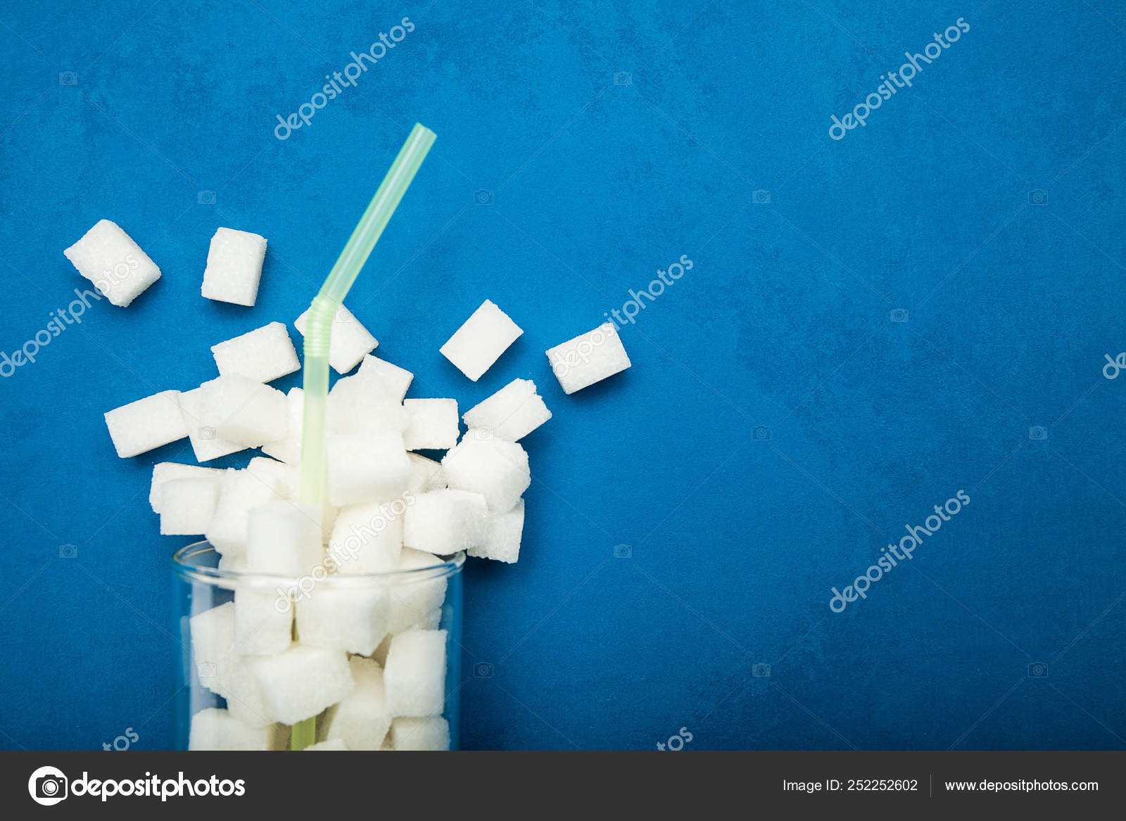 Spilled sugar from a glass on a blue background. Giant sugar con ...