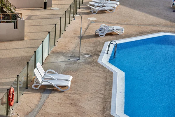 A few empty chaise lounges stand at the luxurious pool, there are no ...
