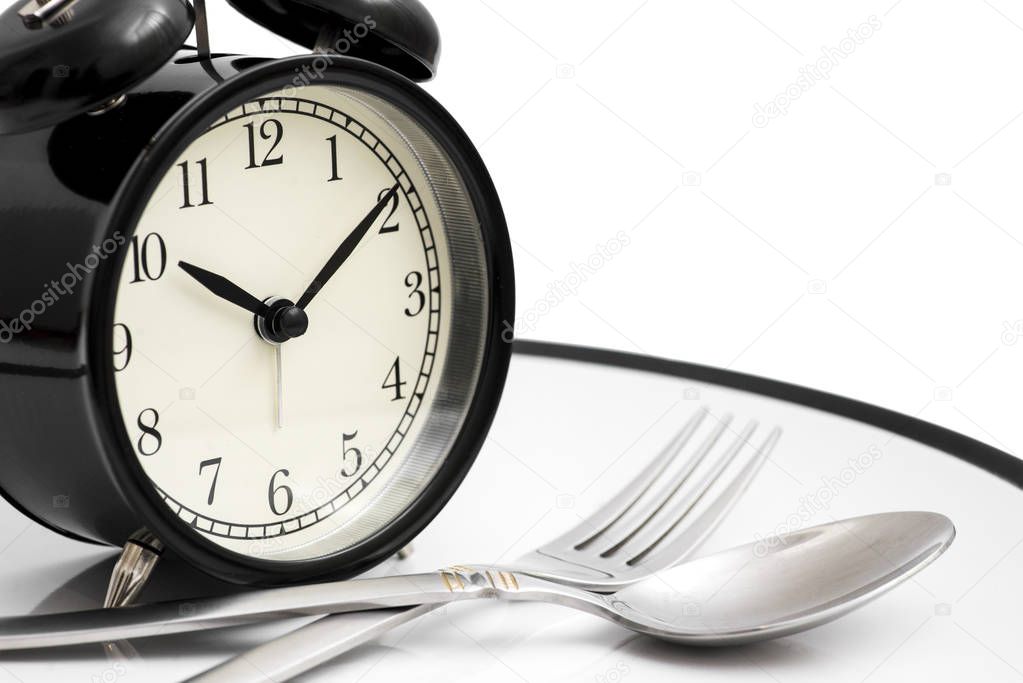 Reloj despertador con tenedor y cuchillo en la placa en blanco. Hora de ...