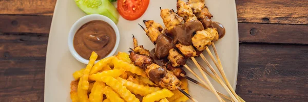 Pollo satay servido con salsa de maní y papas fritas. Bali, Lifestyle BANNER, formato largo 2024