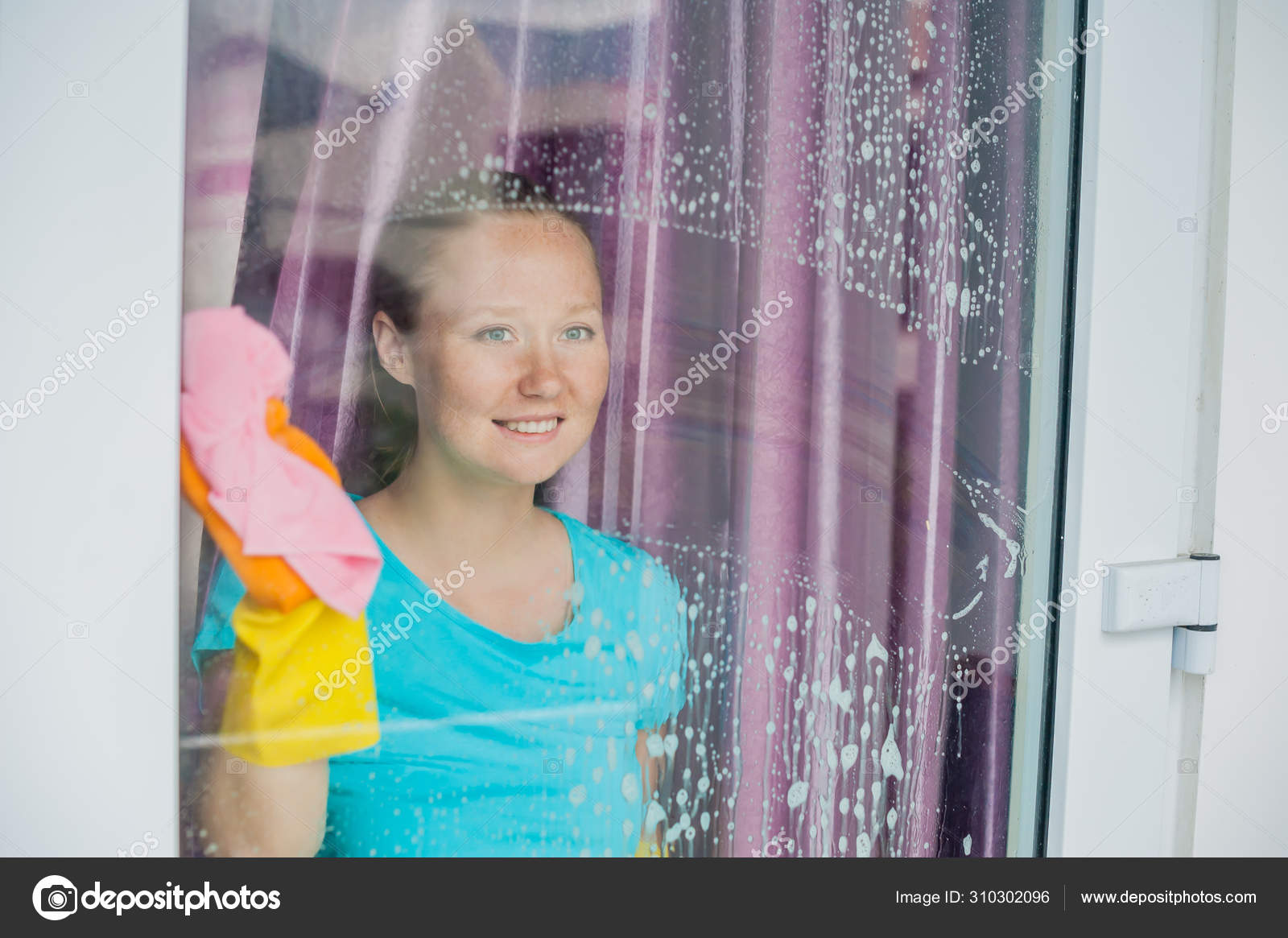 Beautiful female maid doing the housework while using a spray, washing ...