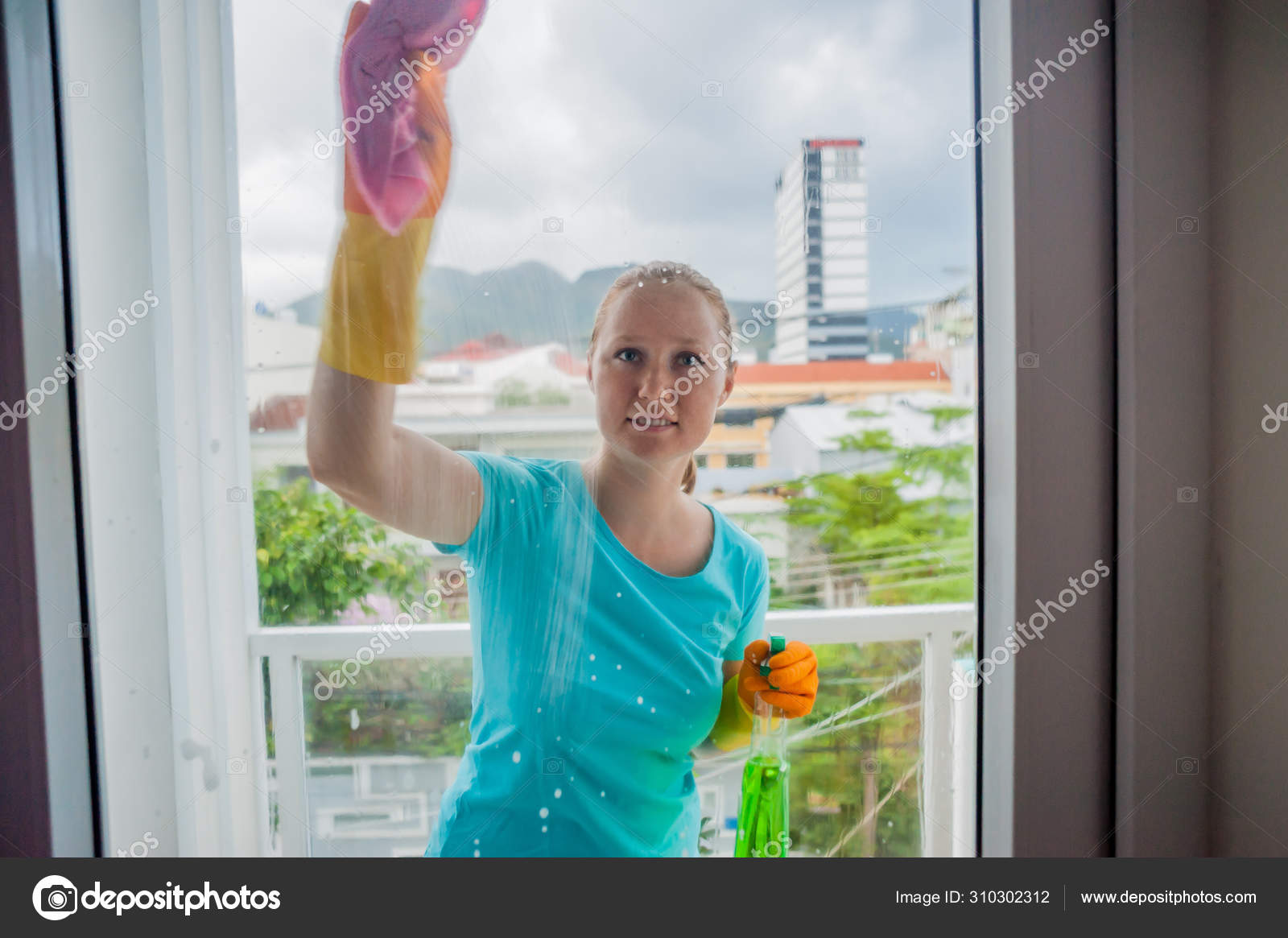 Beautiful female maid doing the housework while using a spray, washing ...