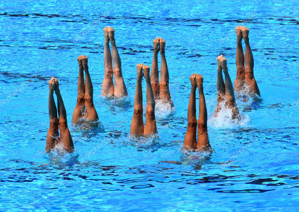 Nadadores sincronizados apuntan fuera del agua en acción. Movimiento ...