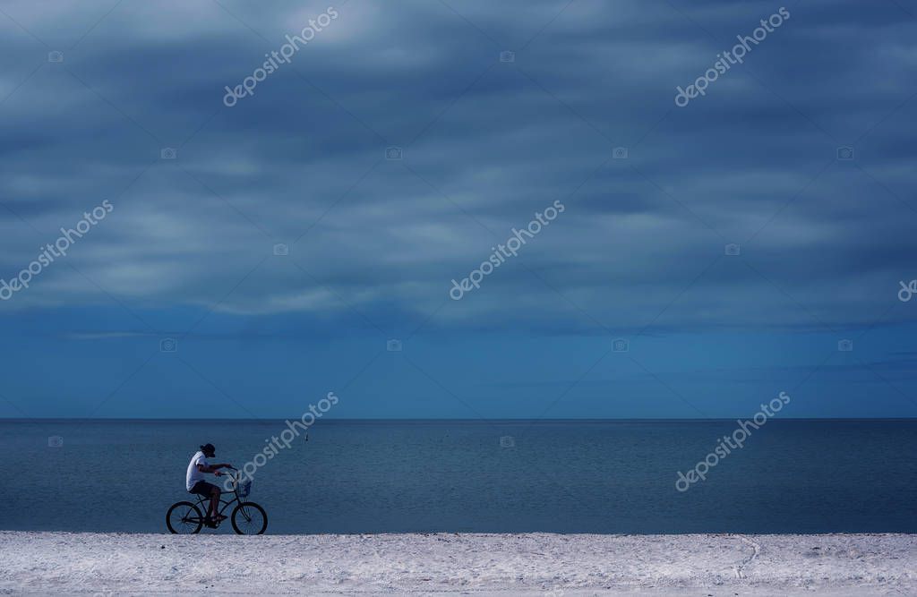 Un ciclista monta en la línea de surf a lo largo de la playa. La costa ...