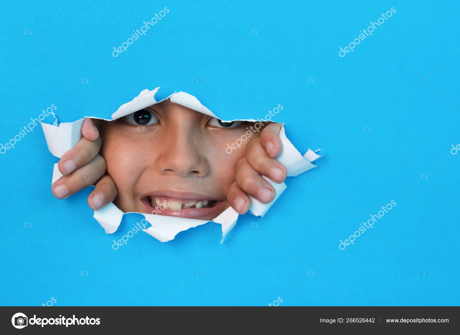 Young boy curiously peeking through ripped paper with a smile on Stock ...