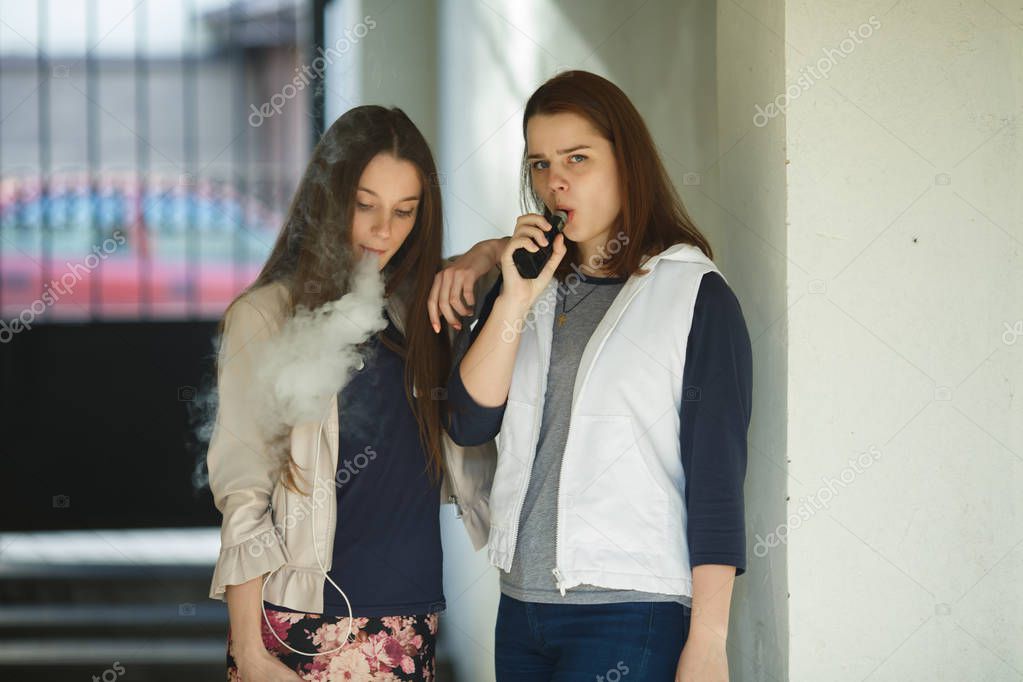 Vape adolescentes. Dos chicas lindas jóvenes en ropa casual fuman ...