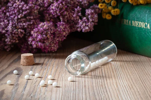 A bottle of homeopathic pills with dried herbs and materia medic ...
