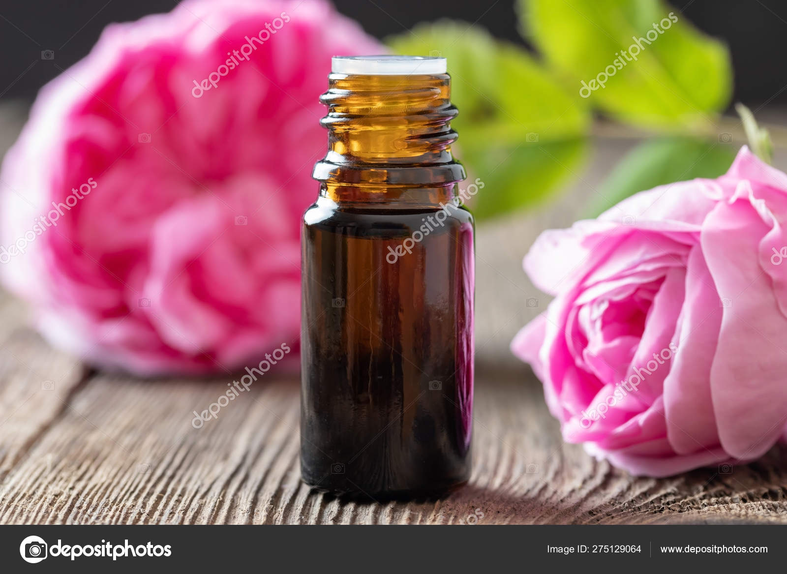 A bottle of rose essential oil with rose flowers — Stock Photo ...