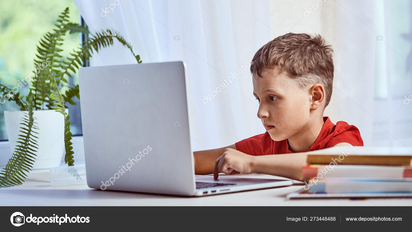 Niño está buscando información en Internet a través de un lapto ...