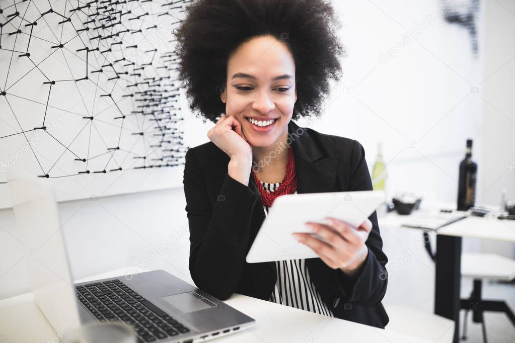 Mujer de negocios afroamericana linda confiada y sonriente sentada en una cafetería moderna y ...