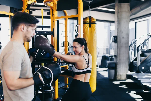 Young attractive woman with instructor on kickboxing training. She ...