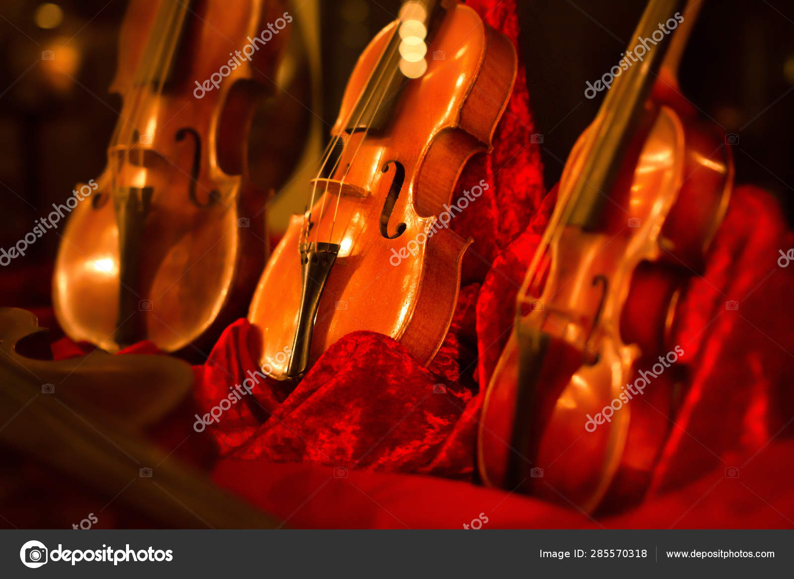 Classical music instruments violins on red velvet illuminated by ...