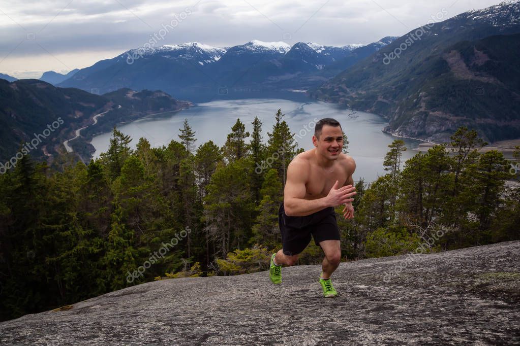 Fit and Muscular Young Man está subiendo la montaña durante un día ...