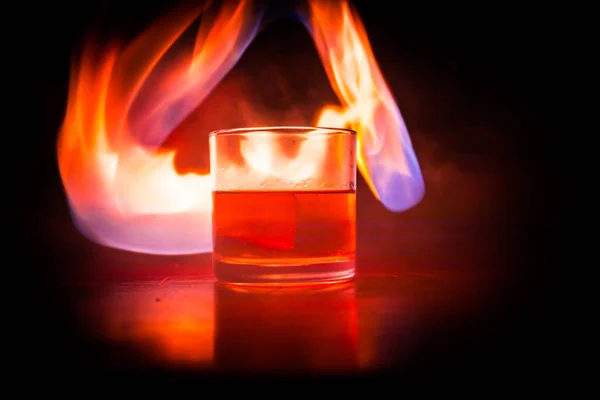 Whiskey in fire concept. Glass of whiskey and ice on wooden surface ...