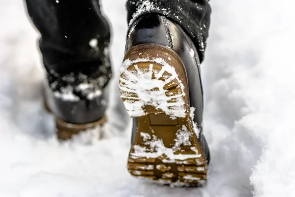 Black boots in snow, person put the step in snow, hiking in winter ...