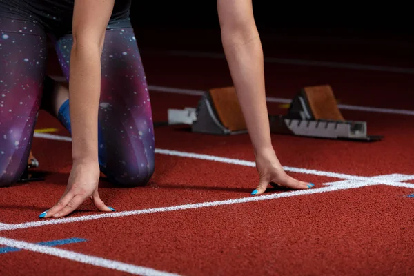 woman sprinter leaving starting blocks on the athletic track. exploding ...