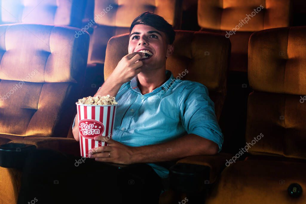 Un joven sonriendo disfrutando con sus palomitas mientras ve una pel cula en el cine 2024